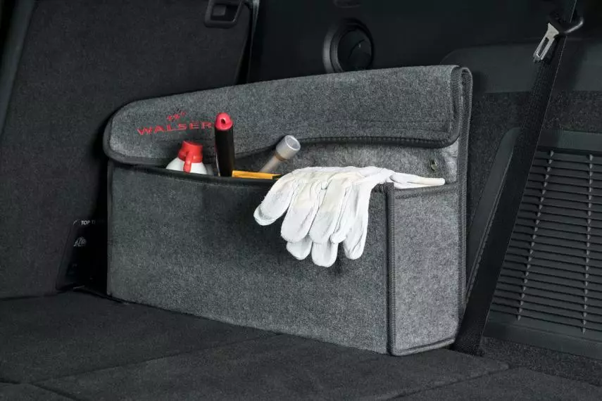 Un sac de rangement gris à moitié ouvert dans le coffre d'une voiture pleine d'accessoires